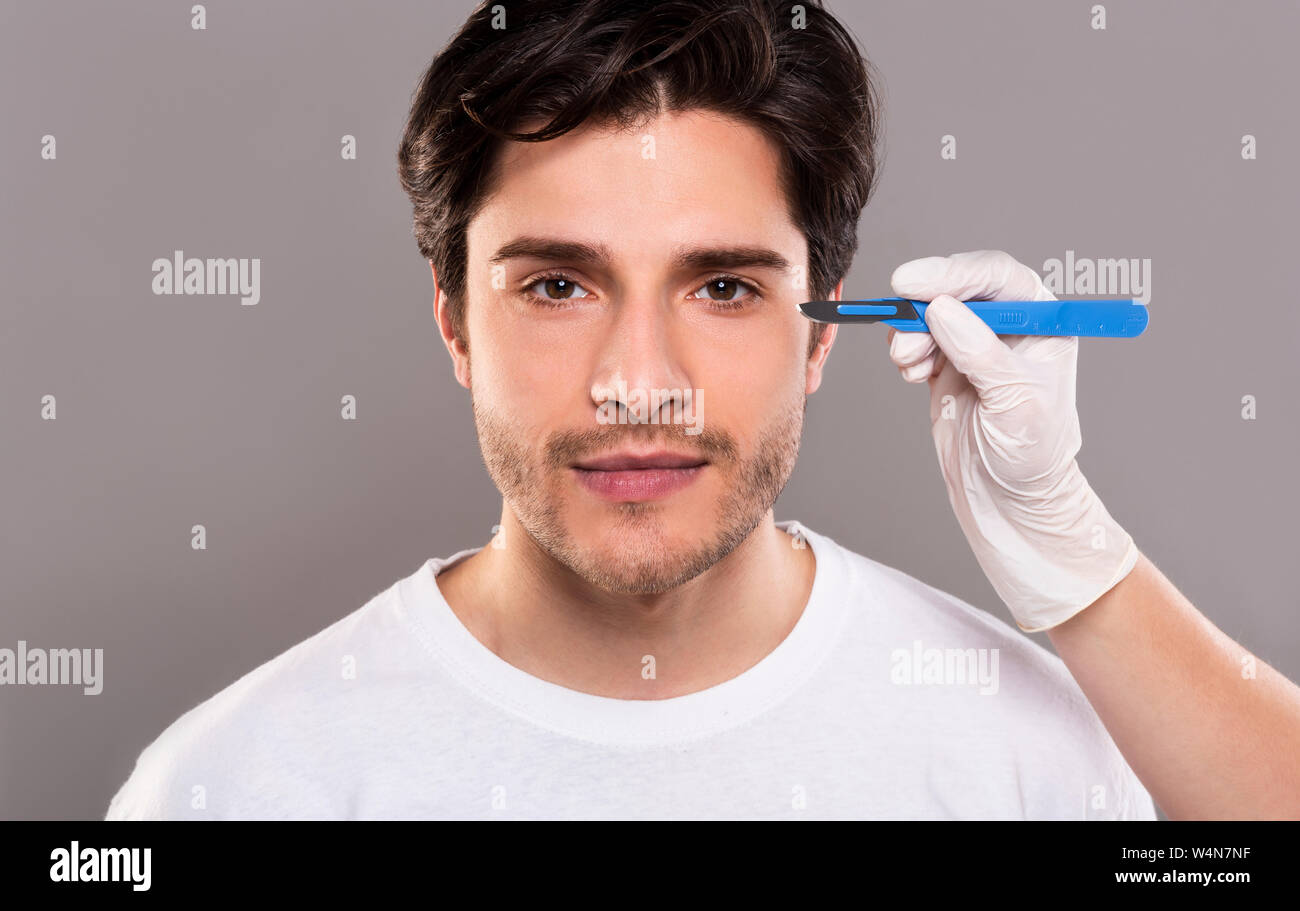 Young man before plastic surgery, doctor hands with scalpel near ...