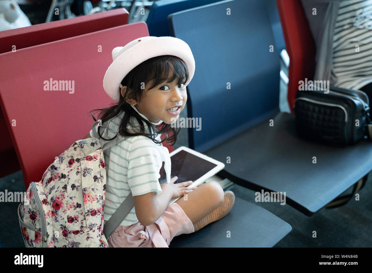 little girl smiling when sitting and hold a tab look at the camera ...