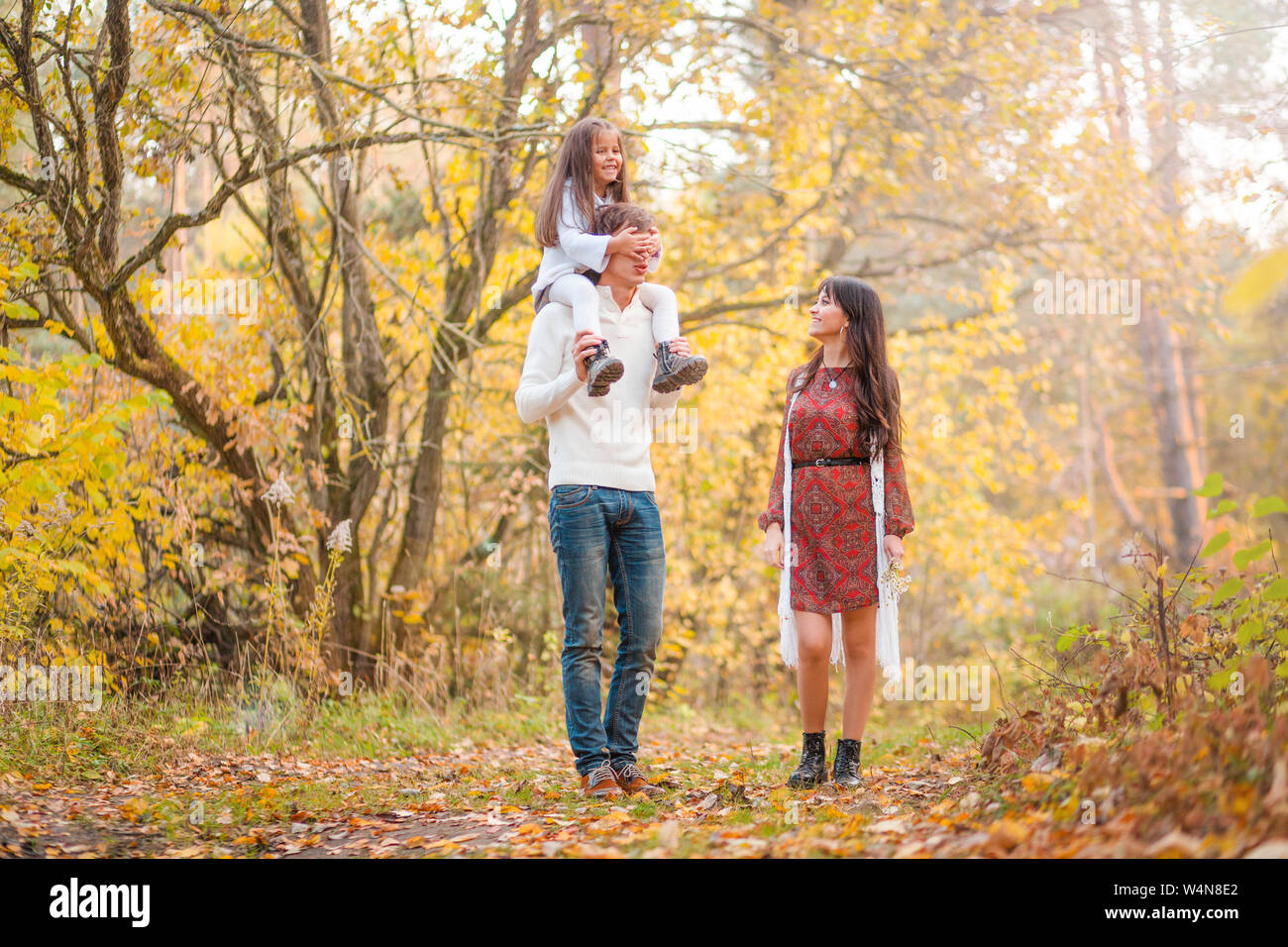 Photo of Mom, dad and daughter walk through the autumn forest. Daughter ...