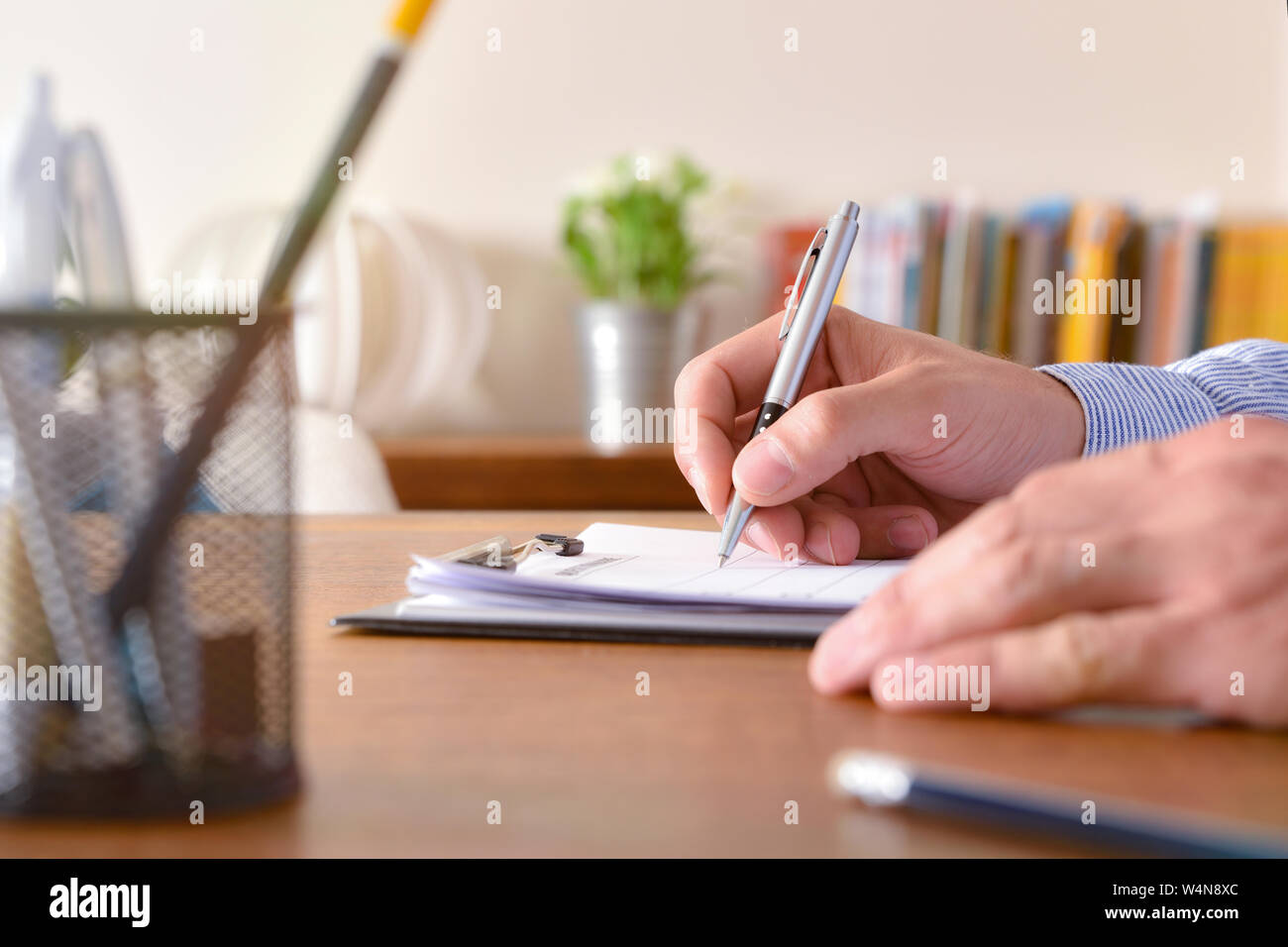 Man filling out a questionnaire on a wooden table close up. Horizontal ...
