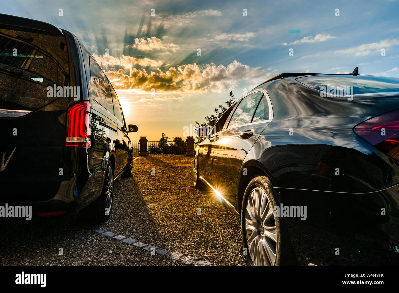 Two luxury cars facing to the colorful sunset, wide angle, summer ...