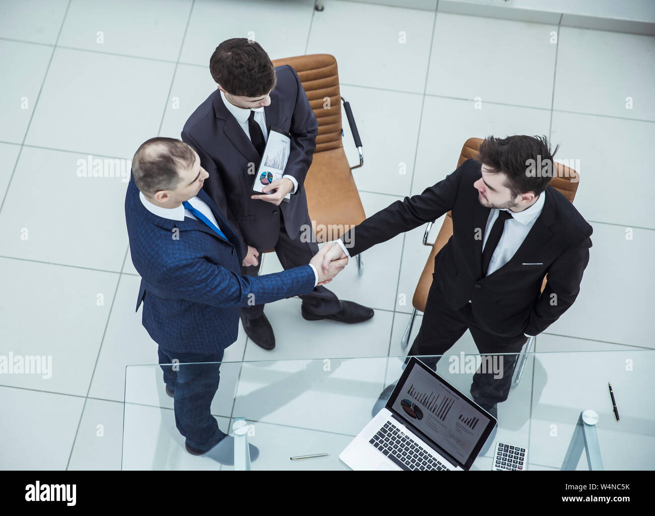 assistant with financial documents and business partners shake hands ...