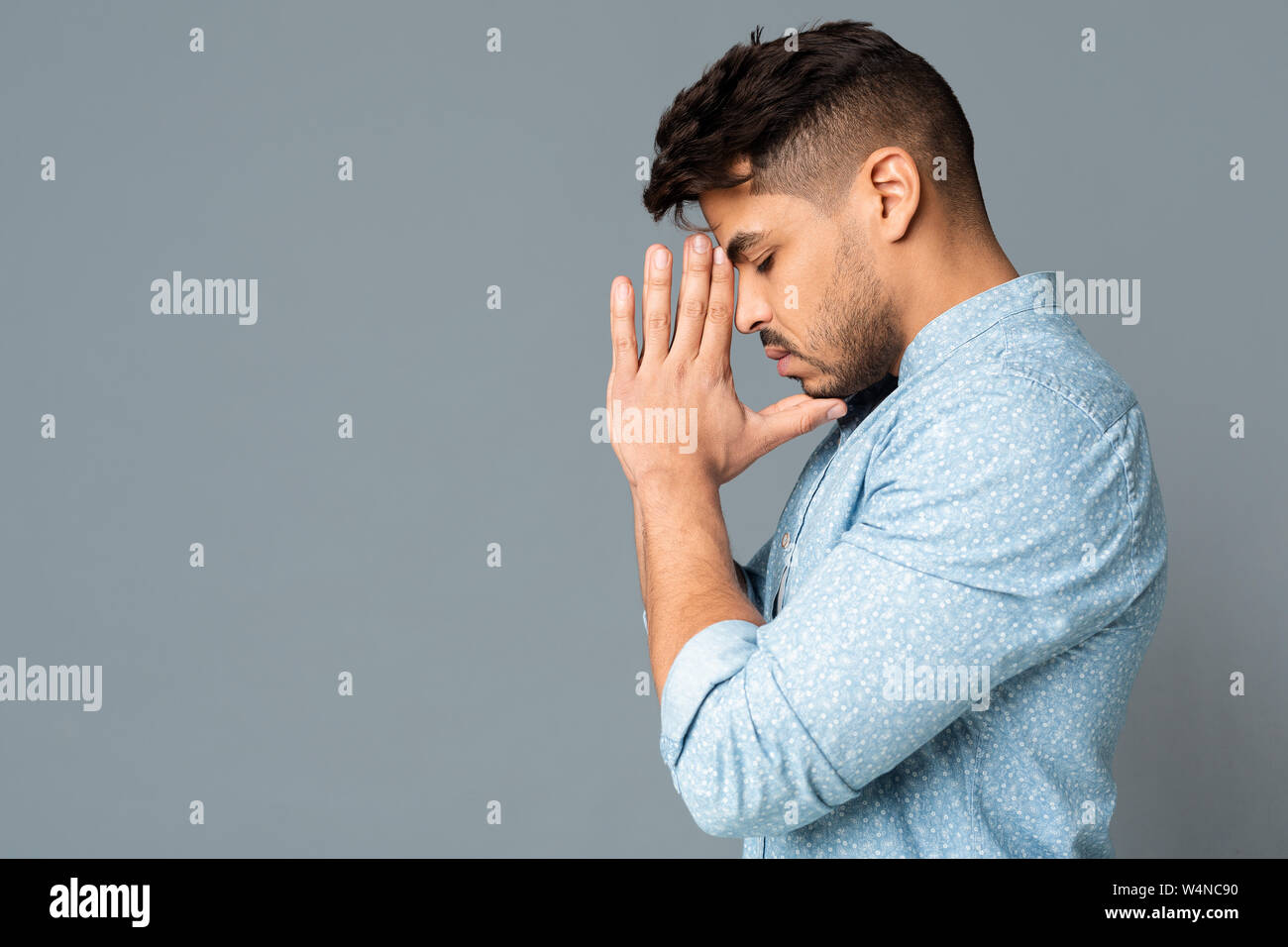 Hopeful Young Man Holding Hands In Praying Gesture. Side View Stock ...