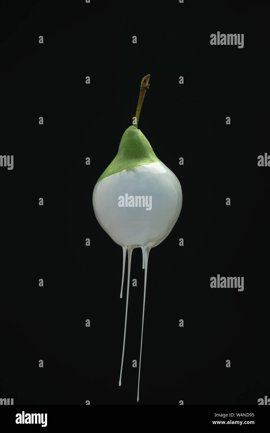 Green Pear dripping white paint on a black background Stock Photo - Alamy