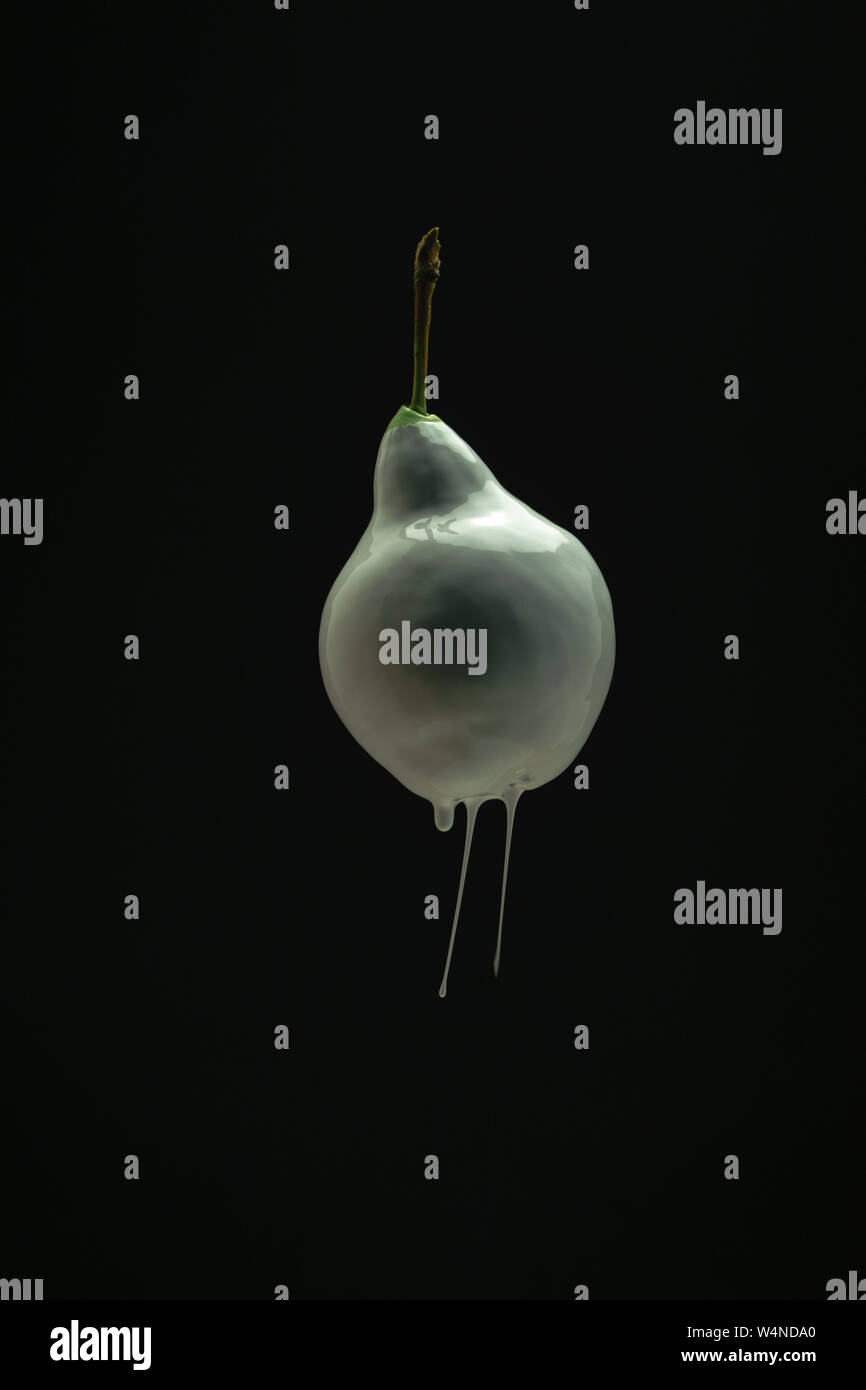 Green Pear dripping white paint on a black background Stock Photo - Alamy