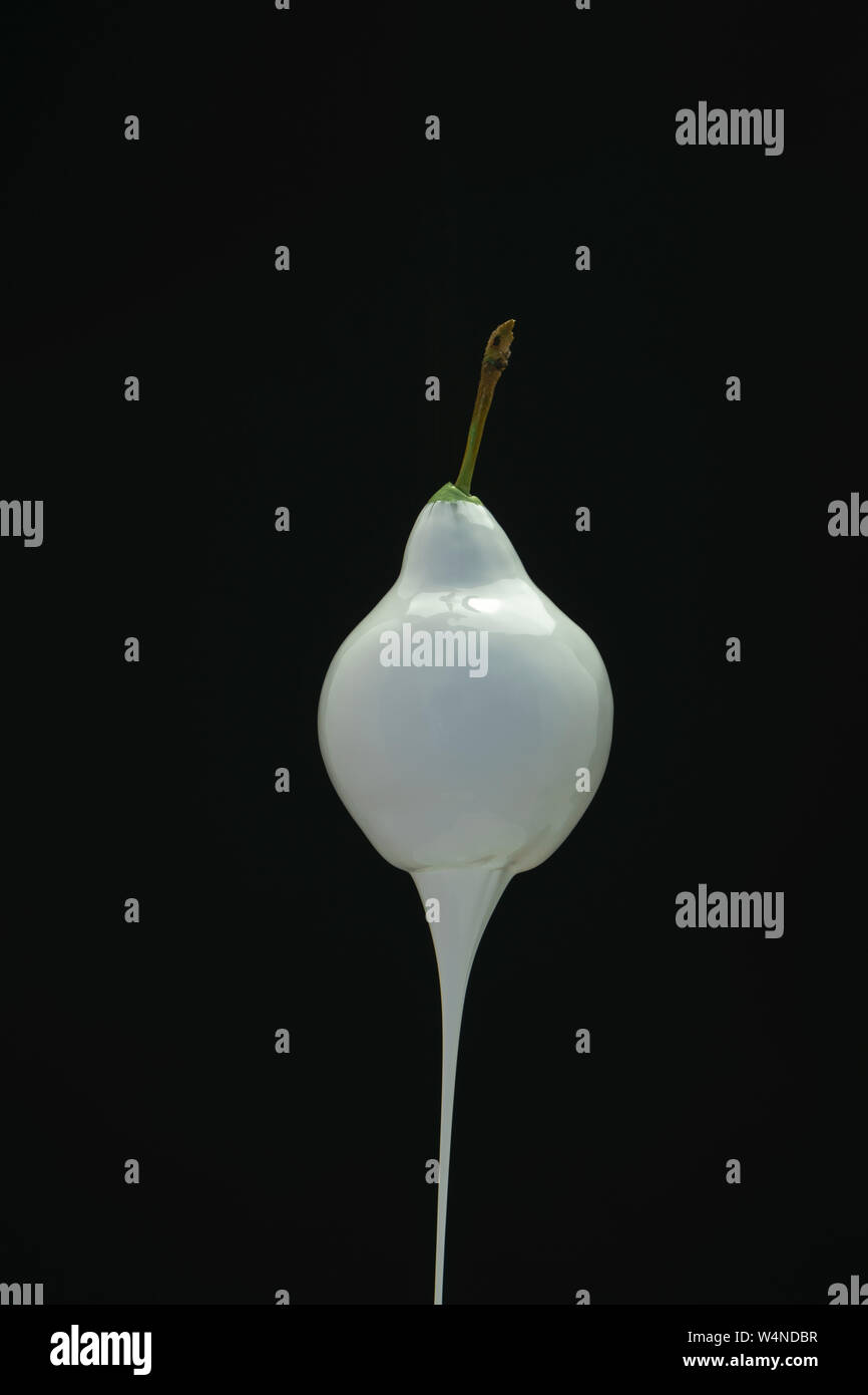 Green Pear dripping white paint on a black background Stock Photo - Alamy