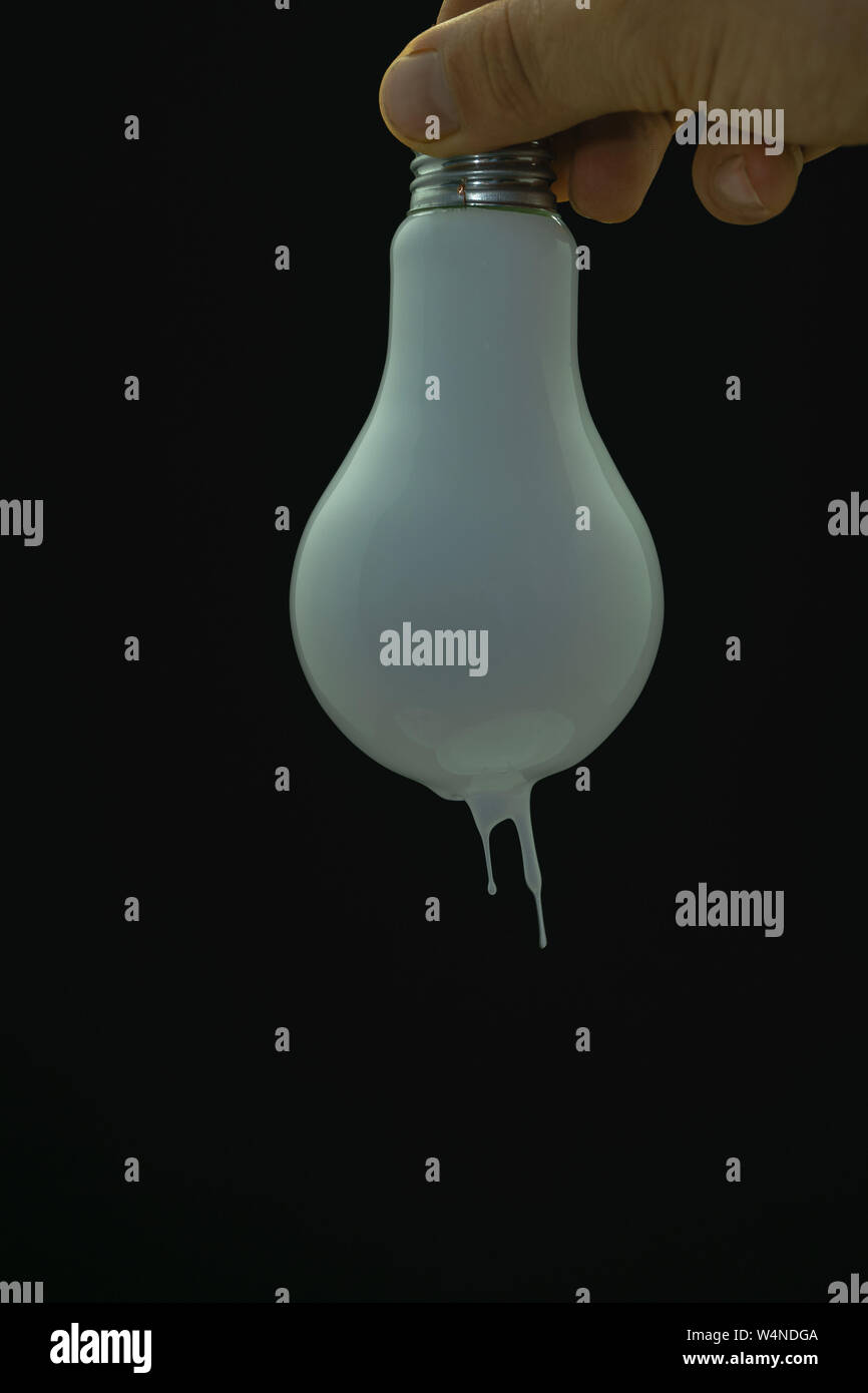 Hand holding big light bulb with dripping white paint on a black ...