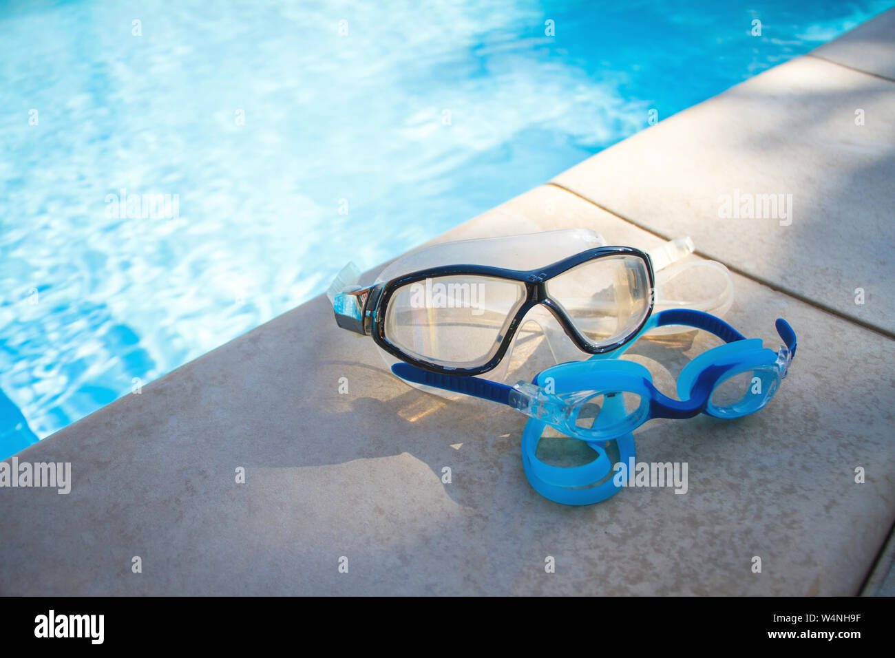 Two blue goggles for swimming lie on the side of the swimming pool ...