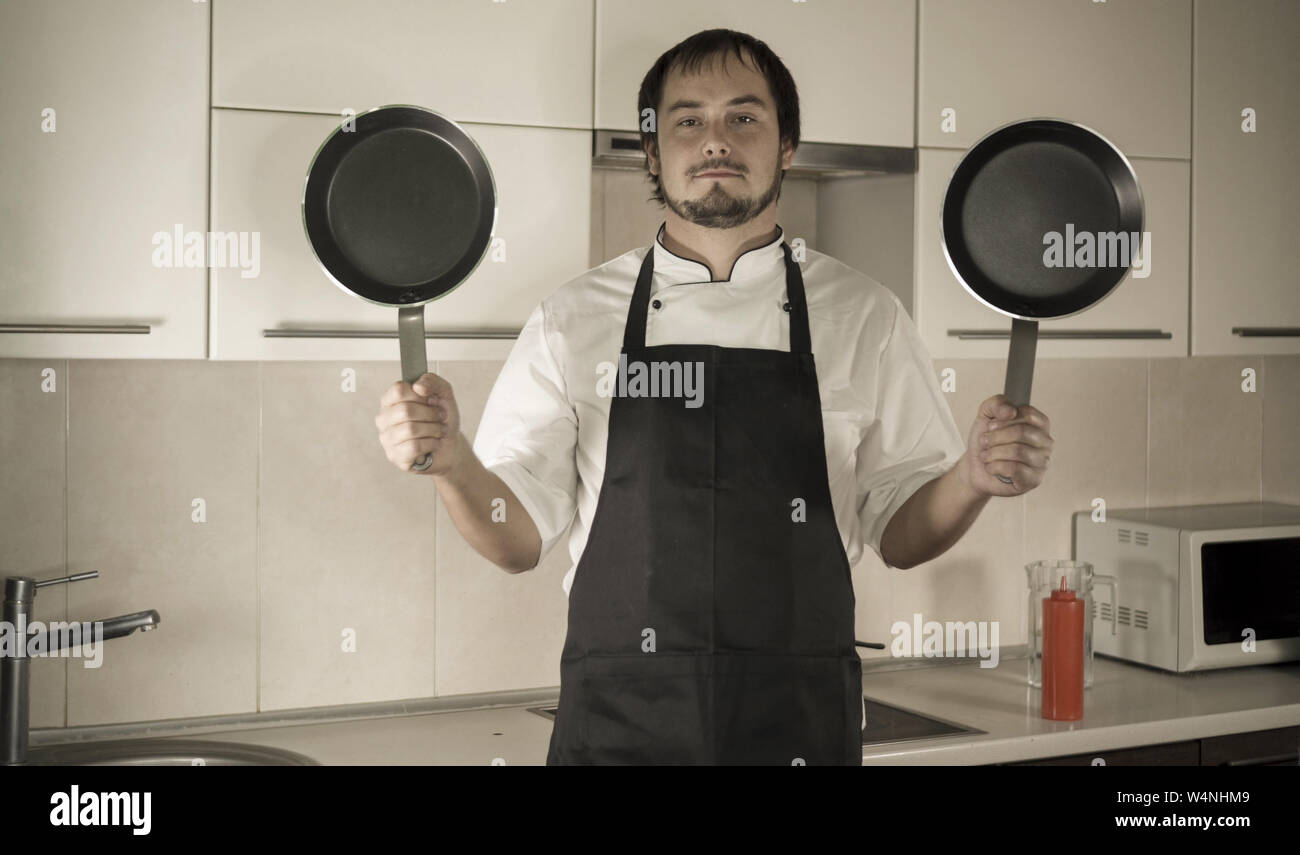 Attractive young funny man dancing while cooking in the kitchen at home ...