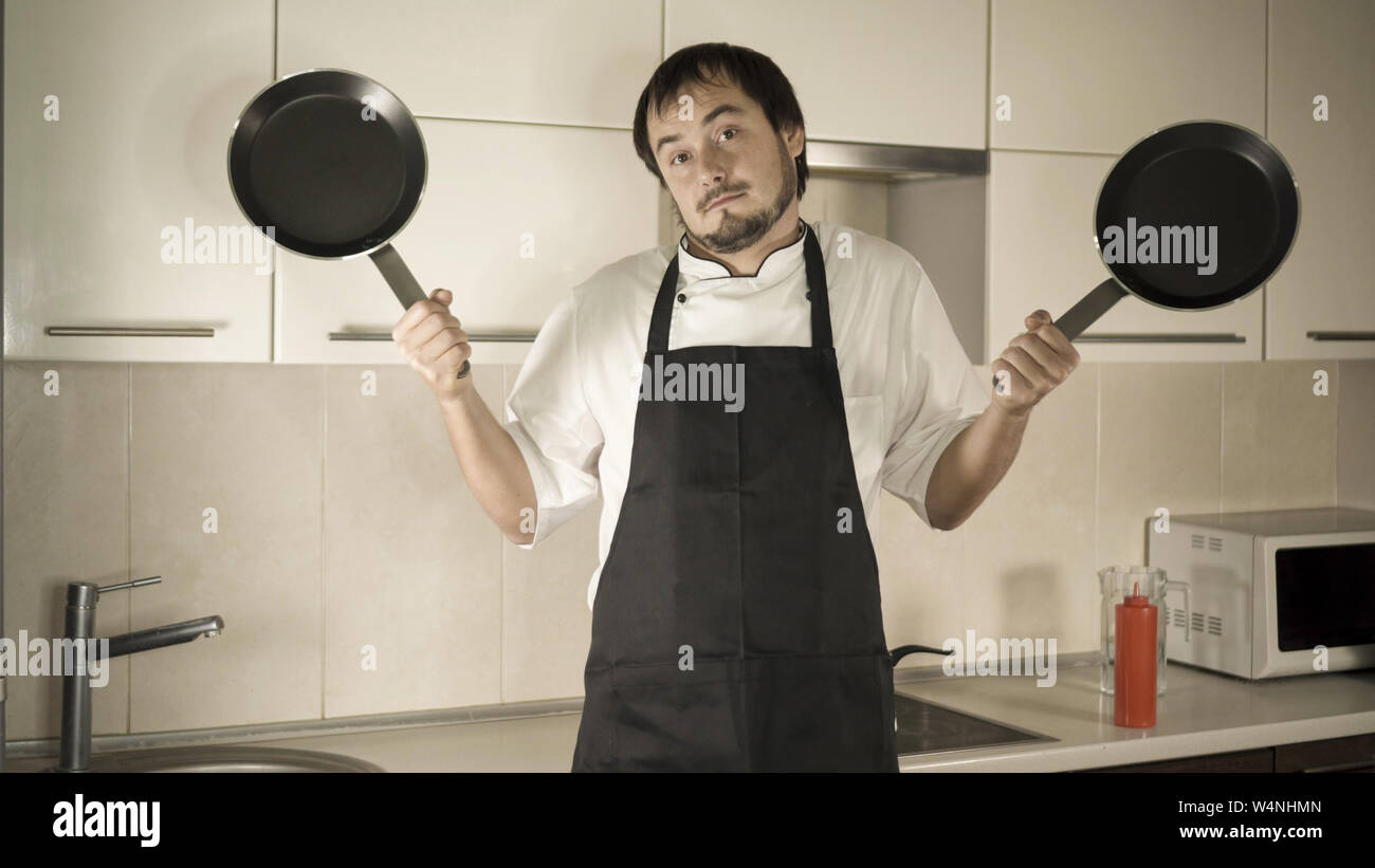 Attractive young funny man dancing while cooking in the kitchen at home ...