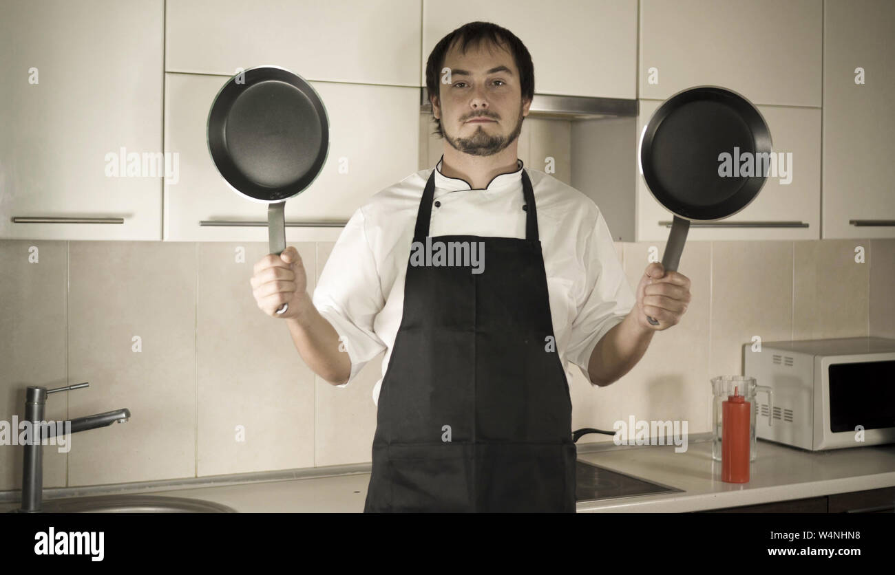 Attractive young funny man dancing while cooking in the kitchen at home ...