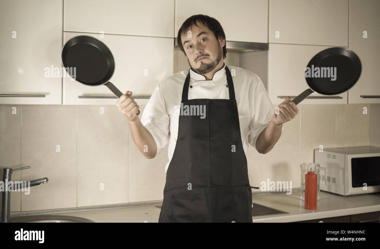 Attractive young funny man dancing while cooking in the kitchen at home ...