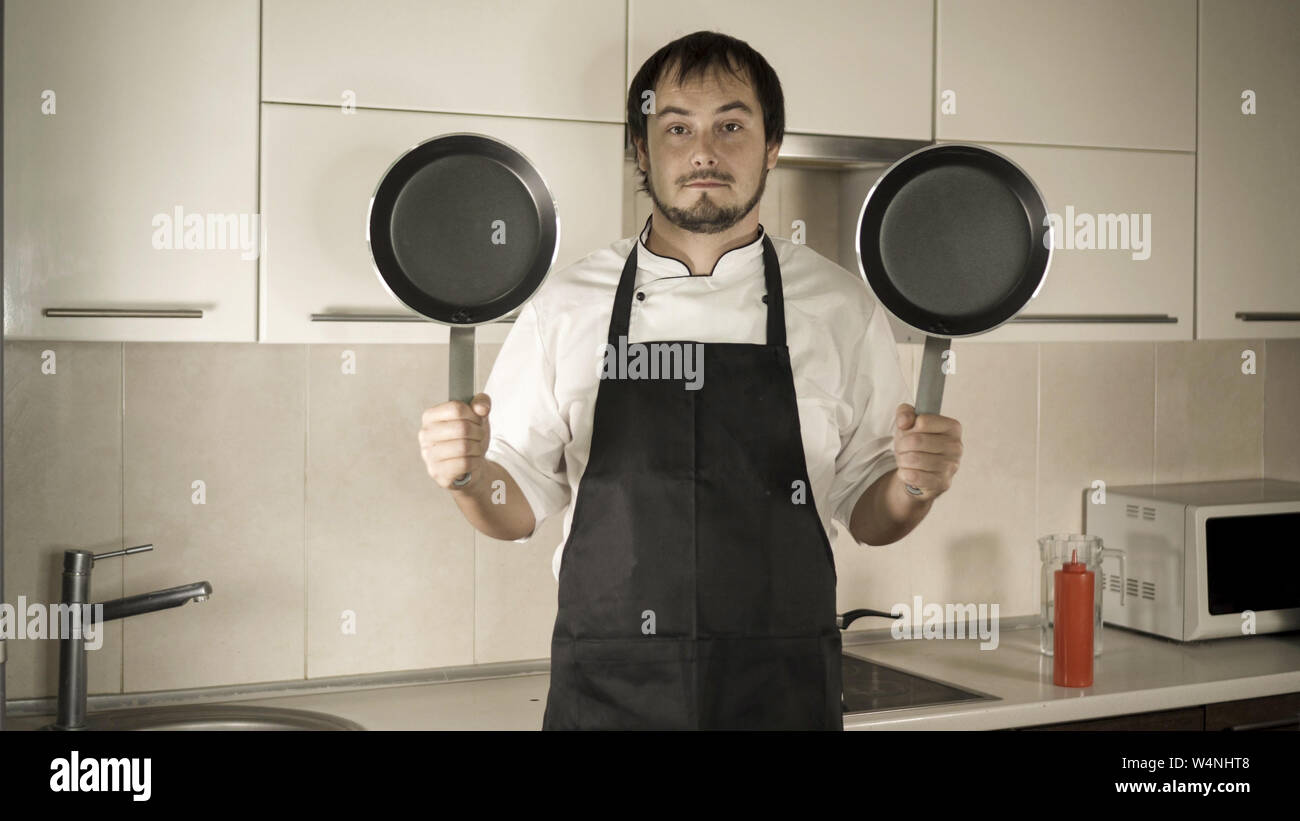 Attractive young funny man dancing while cooking in the kitchen at home ...