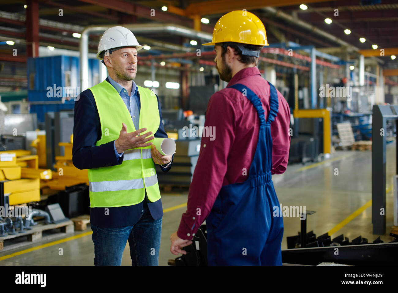 Two engineers in working uniforms and protective helmets have a work ...