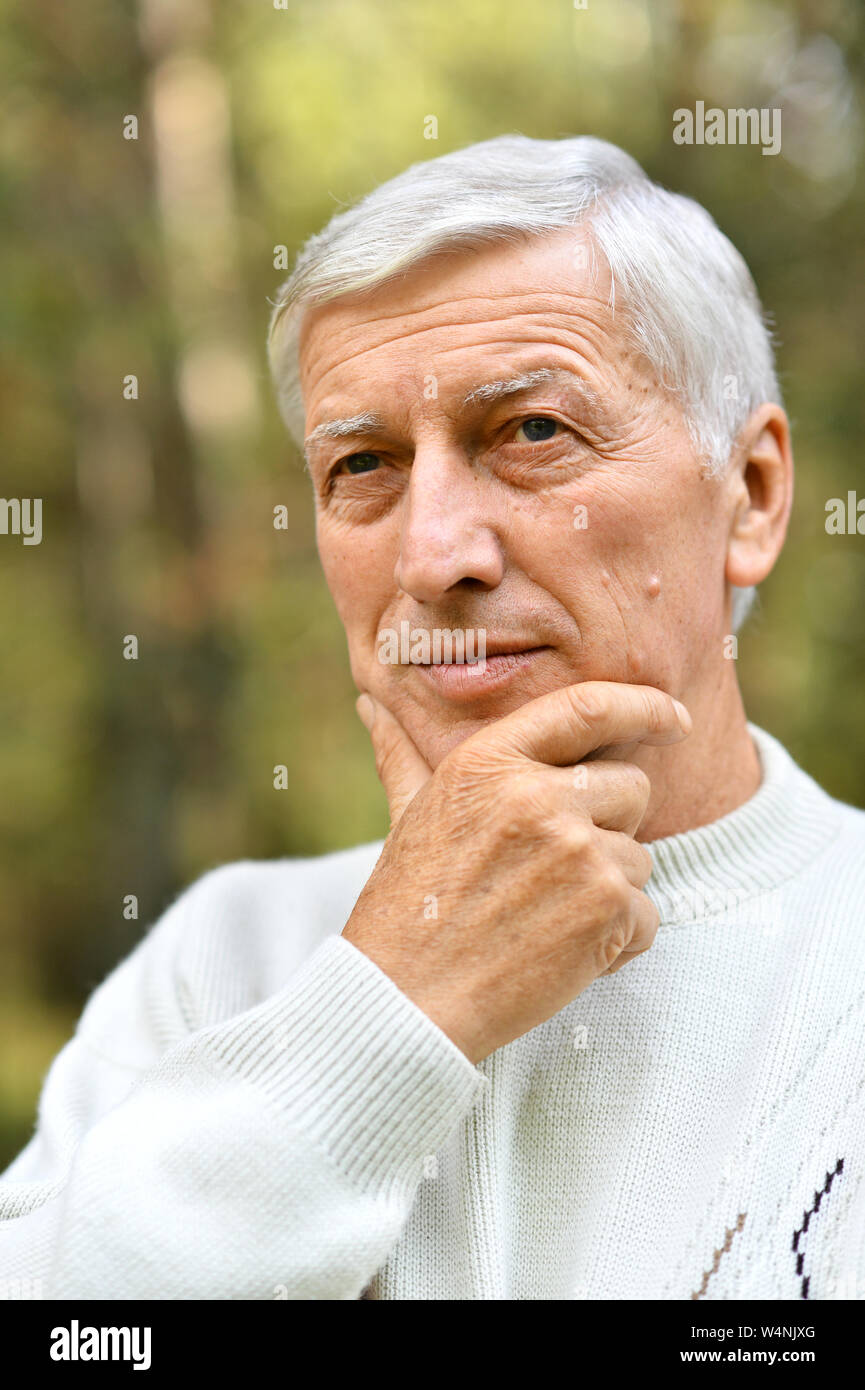 Serious senior man in park on green background Stock Photo - Alamy