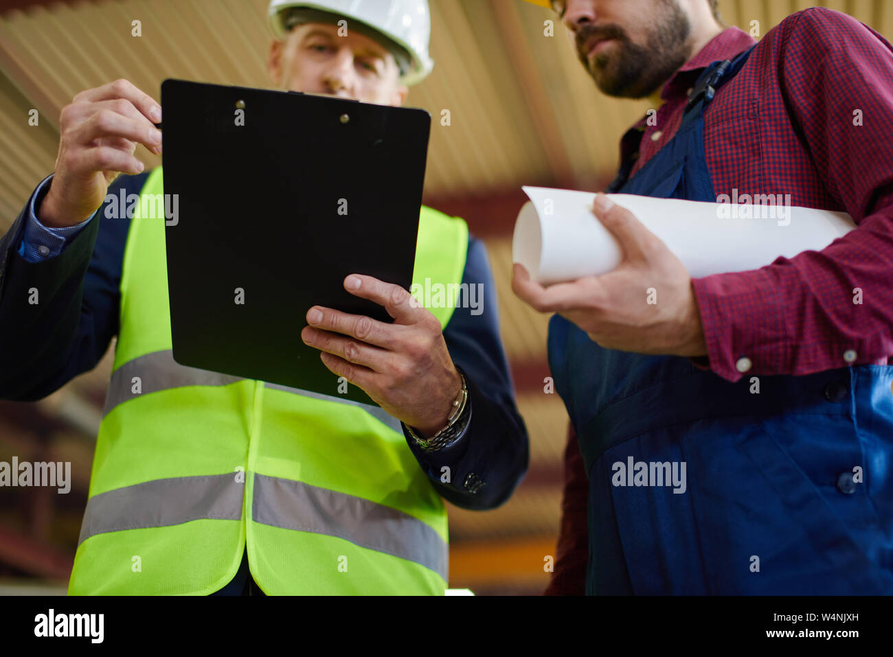 Two engineers in the uniform working on some paperwork involving ...