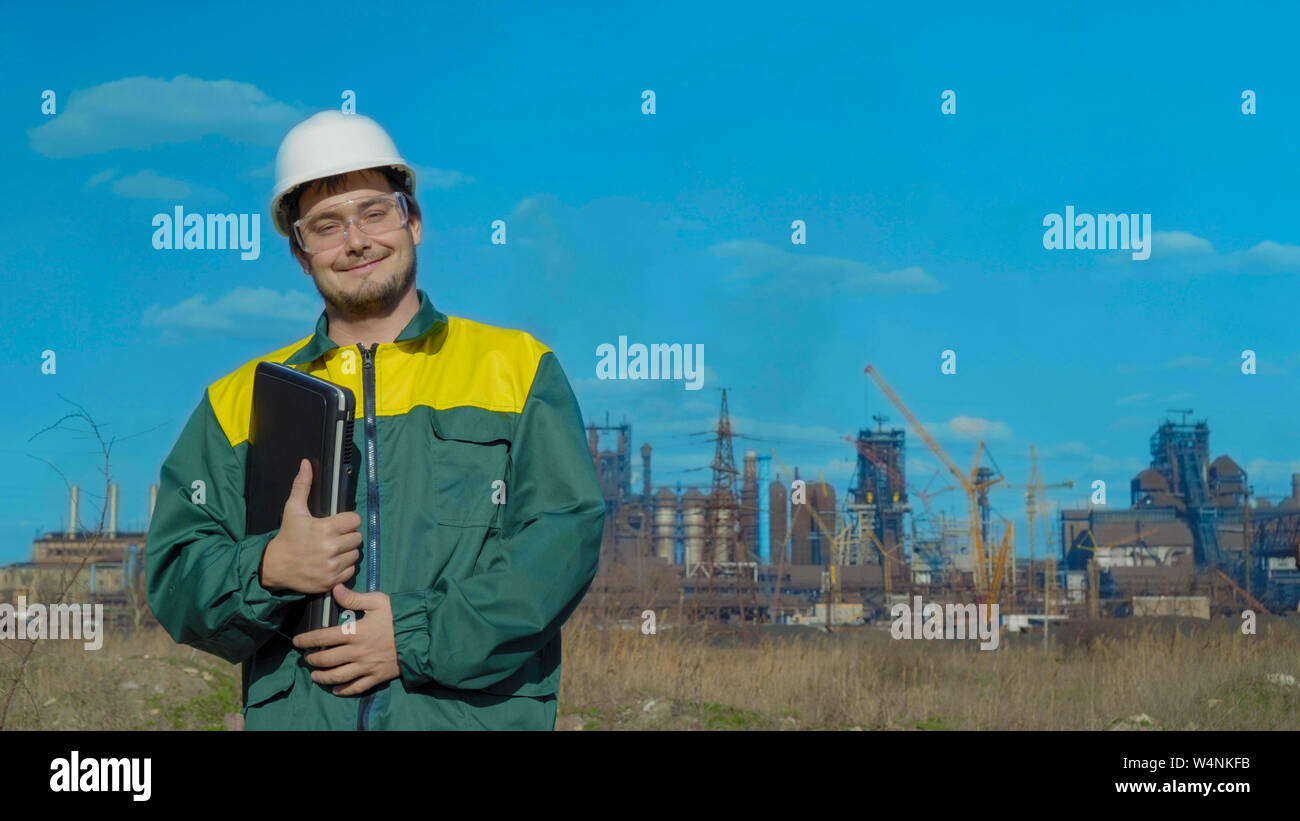 The male engineer projects the work. Sunny day and clouds. The man is dressed in a green ...