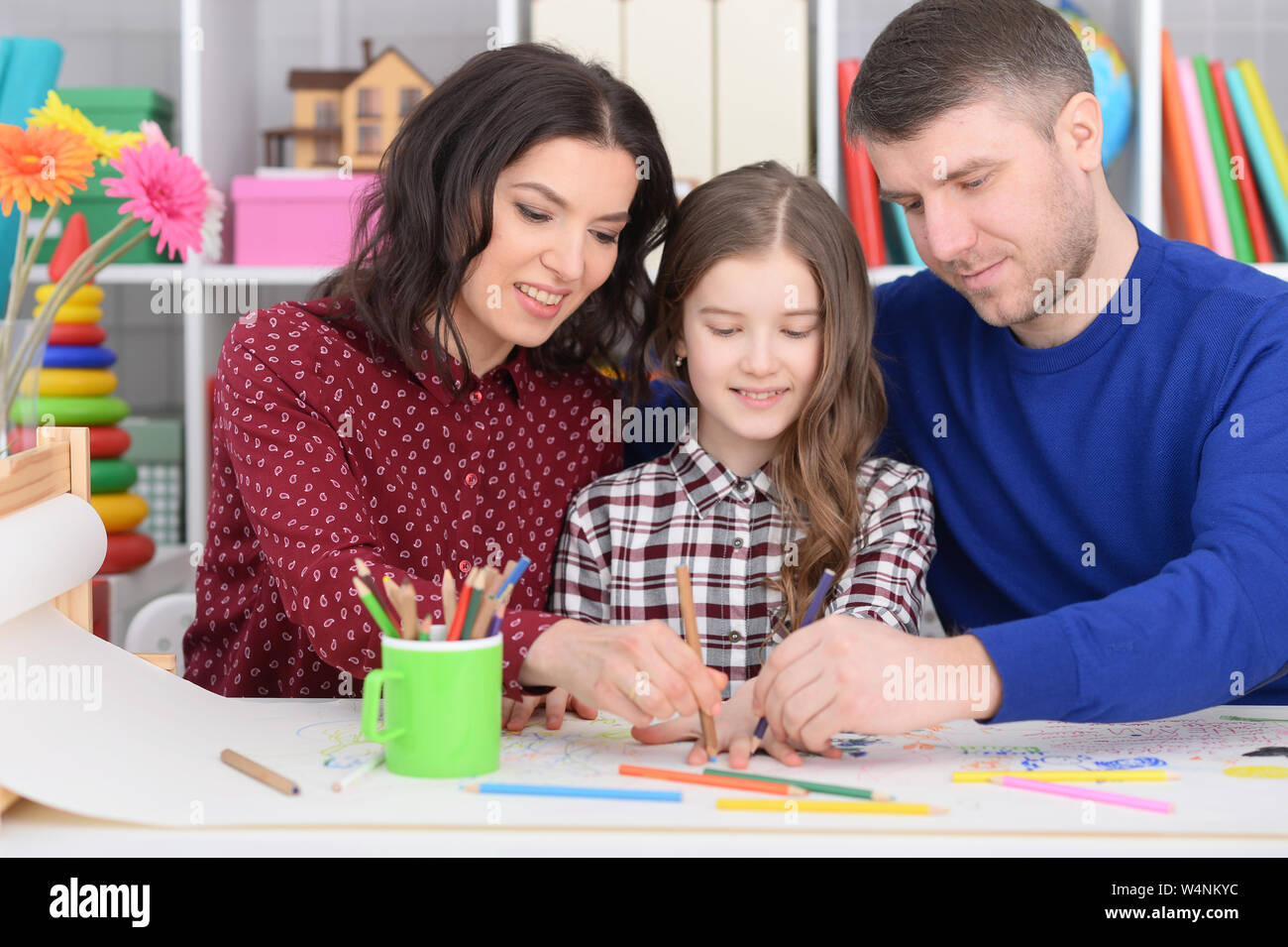Parents and daughter doing homework together in room Stock Photo - Alamy