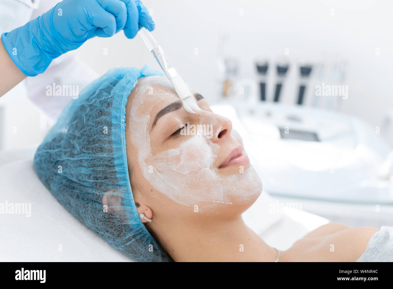 A professional cosmetologist applies a nourishing cream on the patient ...