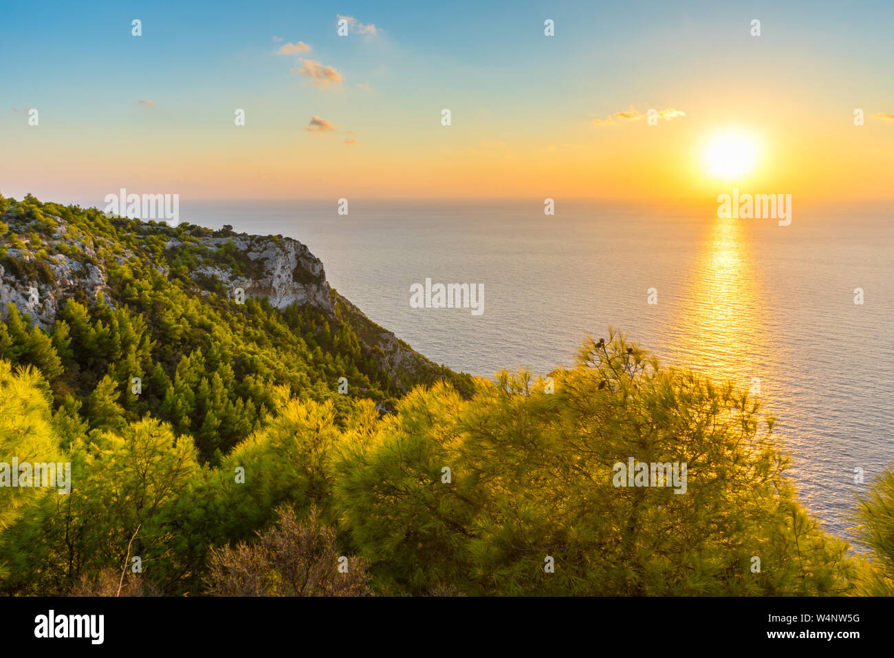 Greece, Zakynthos, Orange sunset light over endless blue ocean behind ...