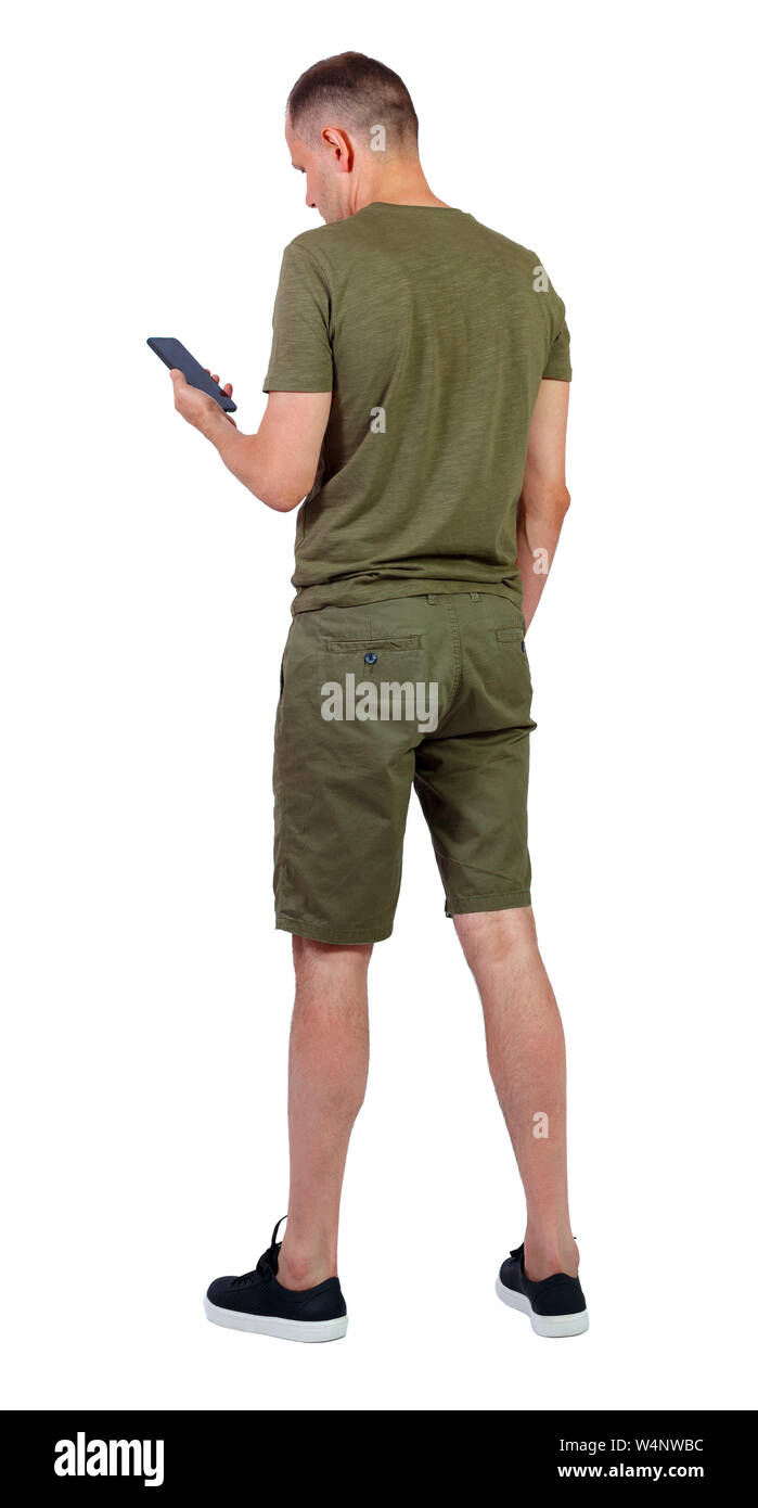 Back view of man in shorts who is looking into the smartphone. rear ...