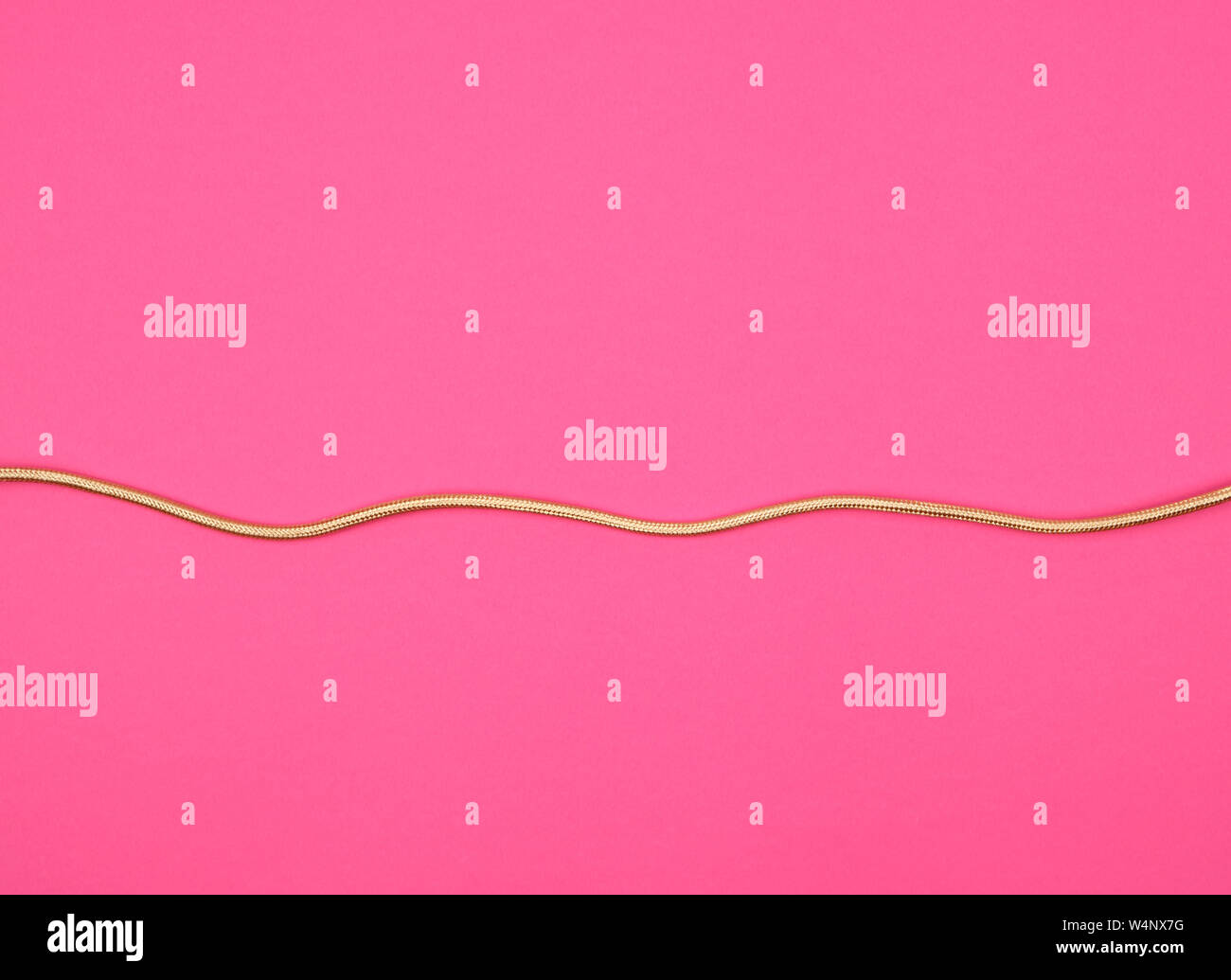 golden cable for equipment in textile winding on a pink background ...