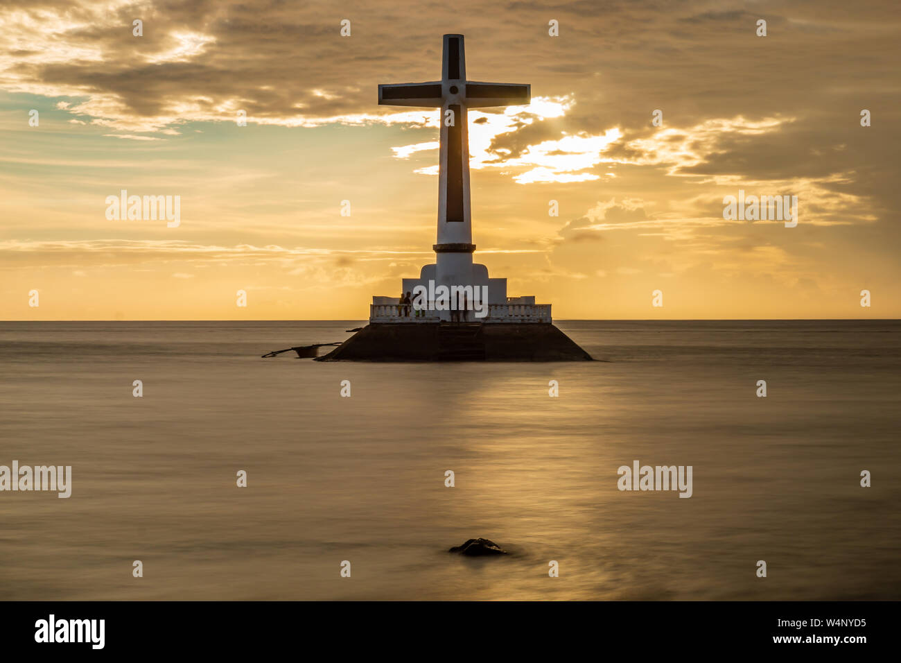 Sunset behind a large cross marking an old, sunken cemetery under the ...