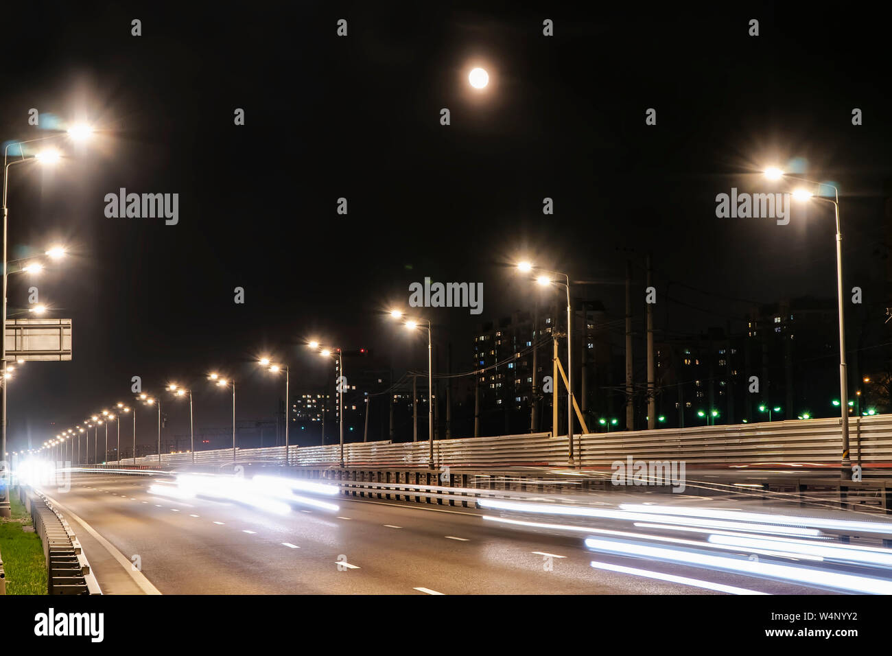 The moon rising over the illuminated highway and the night city Stock ...