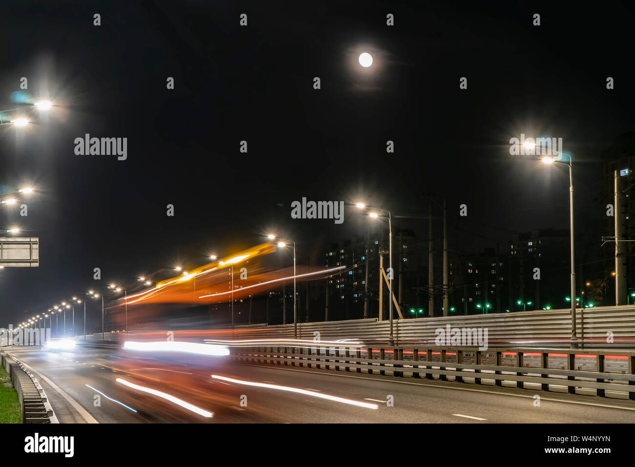 The moon rising over the illuminated highway and the night city Stock ...