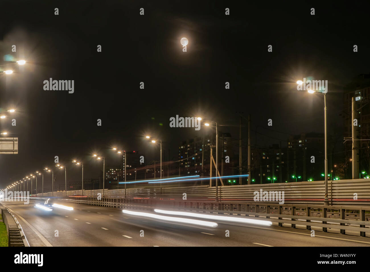 The moon rising over the illuminated highway and the night city Stock ...