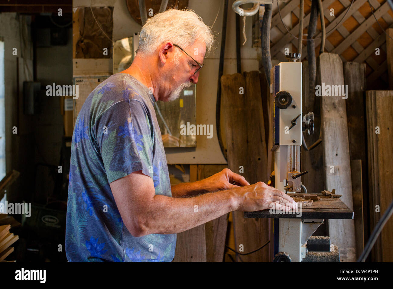 Side view of an elderly gentleman cutting wood with a band saw Stock ...