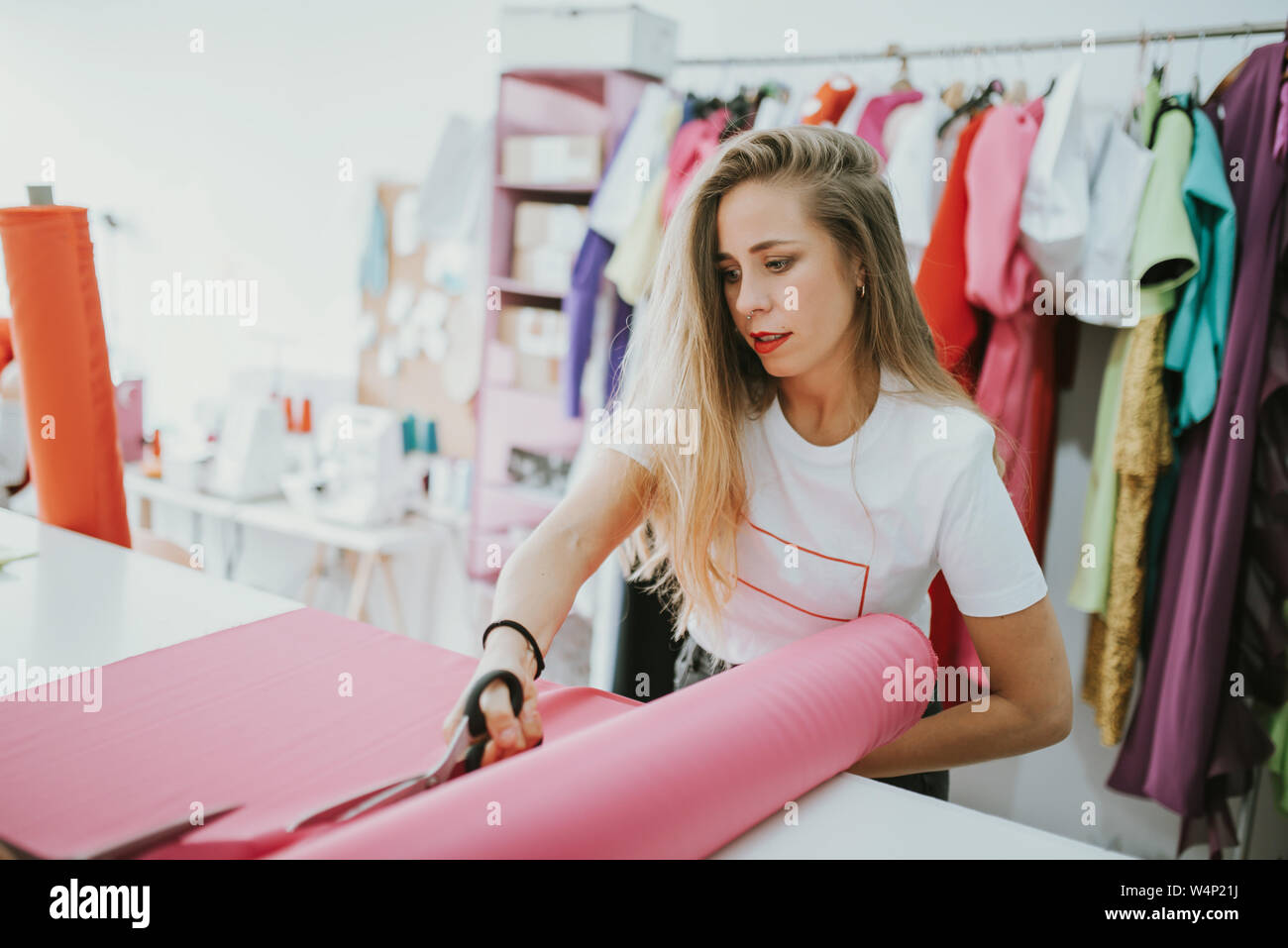 Fashion designer cutting fabric textile in a studio Stock Photo - Alamy