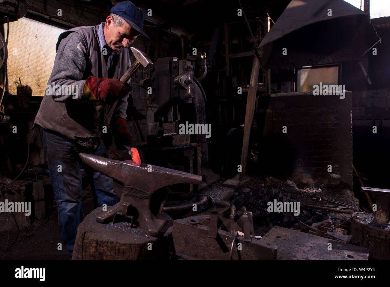 blacksmith manually forging the red hot molten metal on the anvil in ...