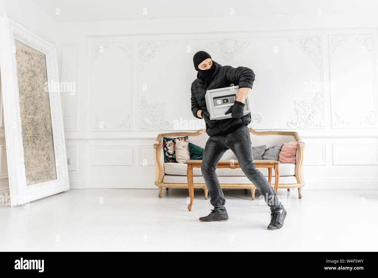 Thief with black balaclava stealing modern Electronic safe box. The ...