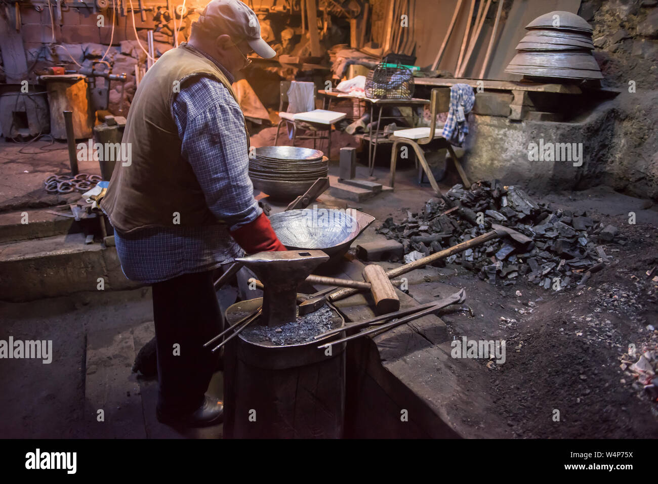 traditional blacksmith manually forging molten metal in smithy workshop ...