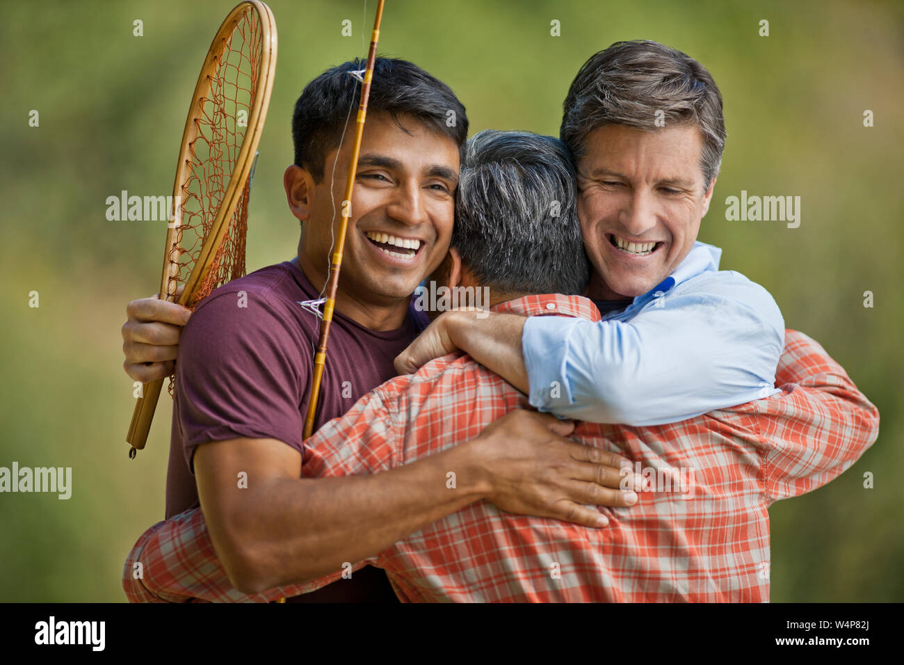 Three friends hugging during a fishing excursion Stock Photo - Alamy