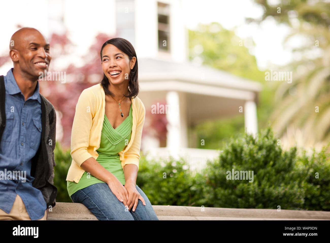 Couple sitting on ledge together Stock Photo - Alamy