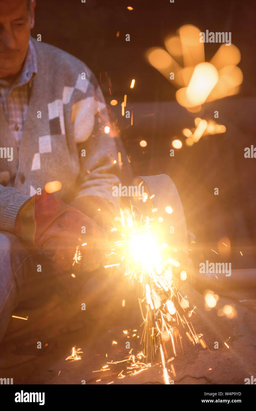the blacksmith polishing metal products making sparks while using a ...