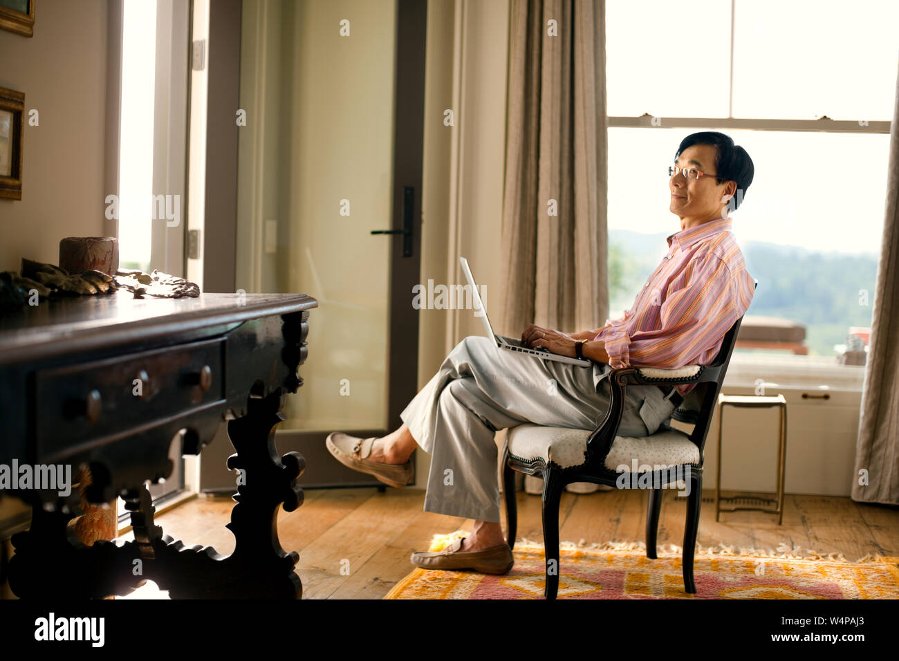 Happy mid adult man working on a laptop computer Stock Photo - Alamy