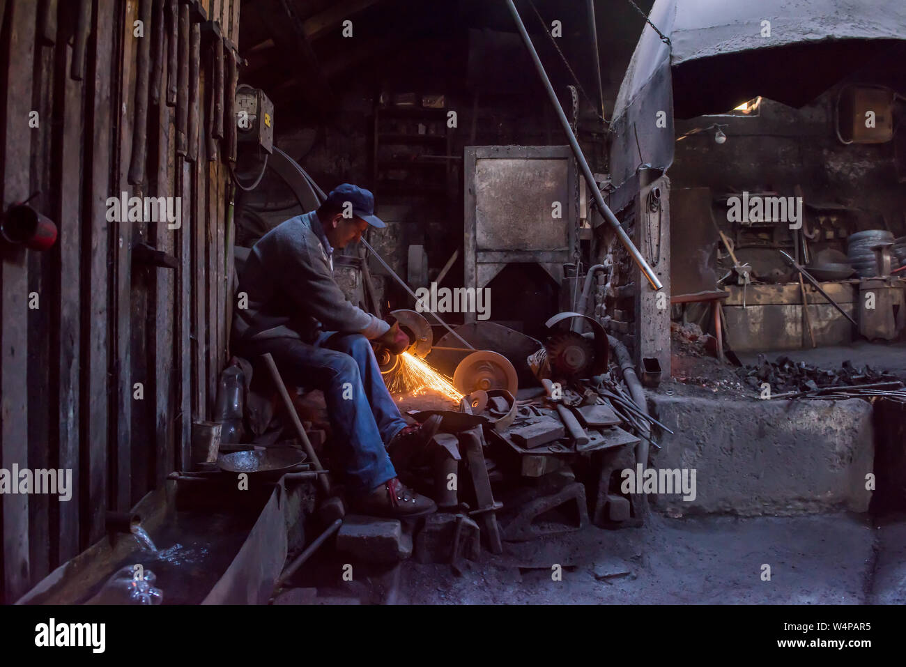 the blacksmith polishing metal products making sparks while using a ...