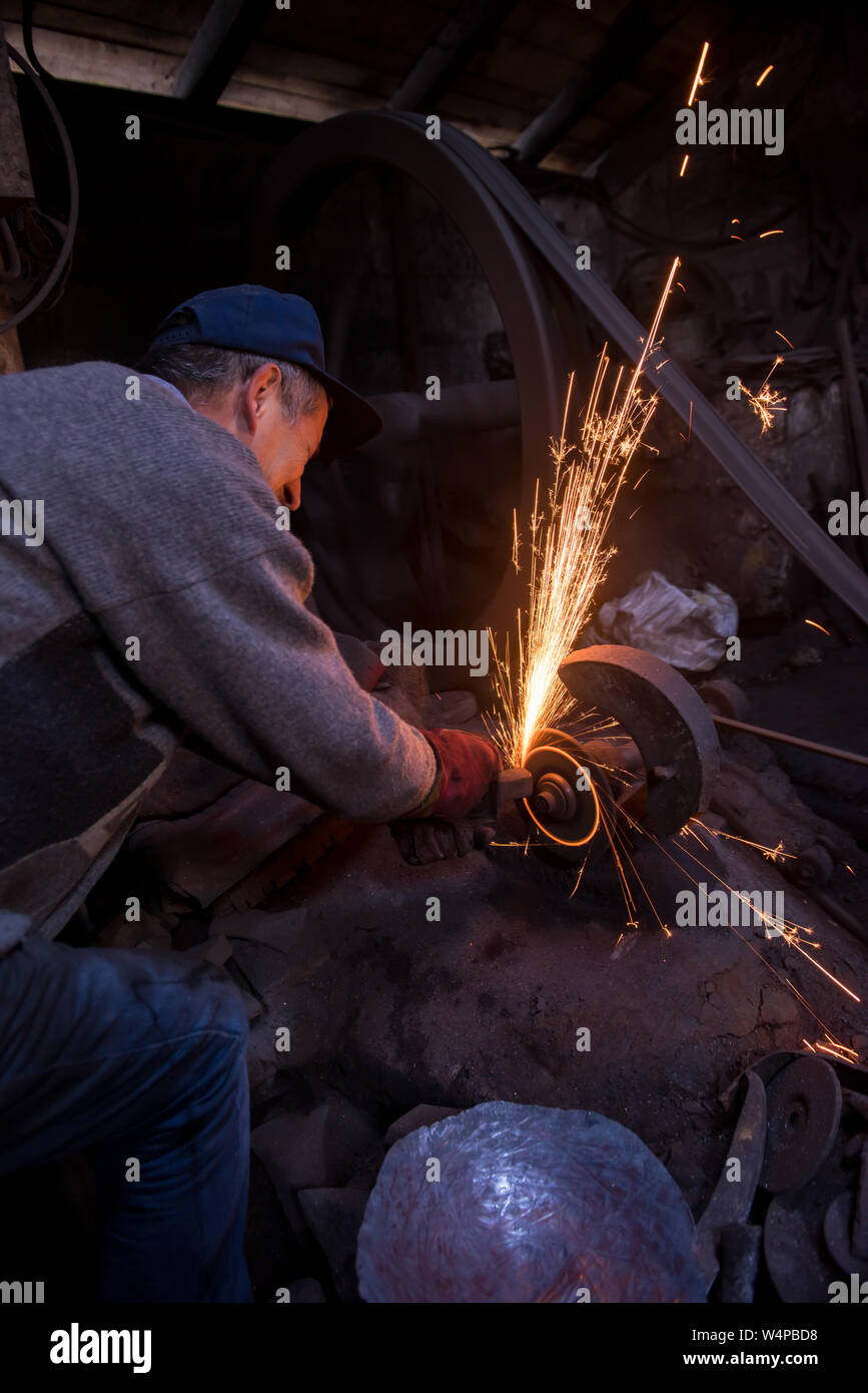 the blacksmith polishing metal products making sparks while using a ...