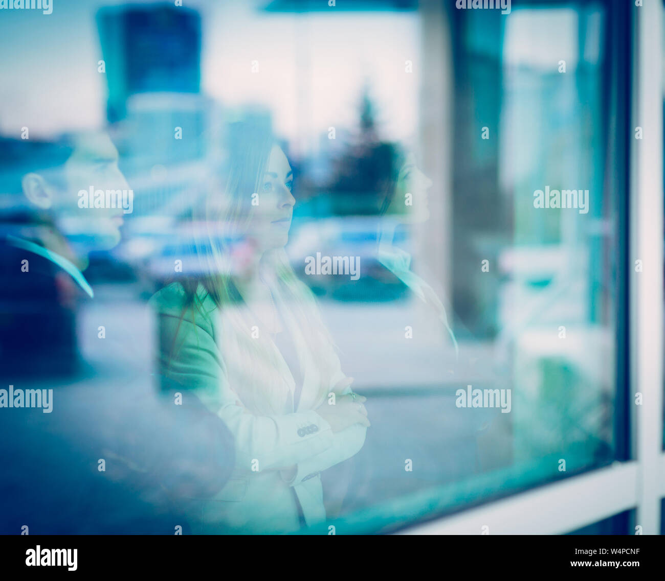 Photo from behind the glass: a successful business team stands in front ...