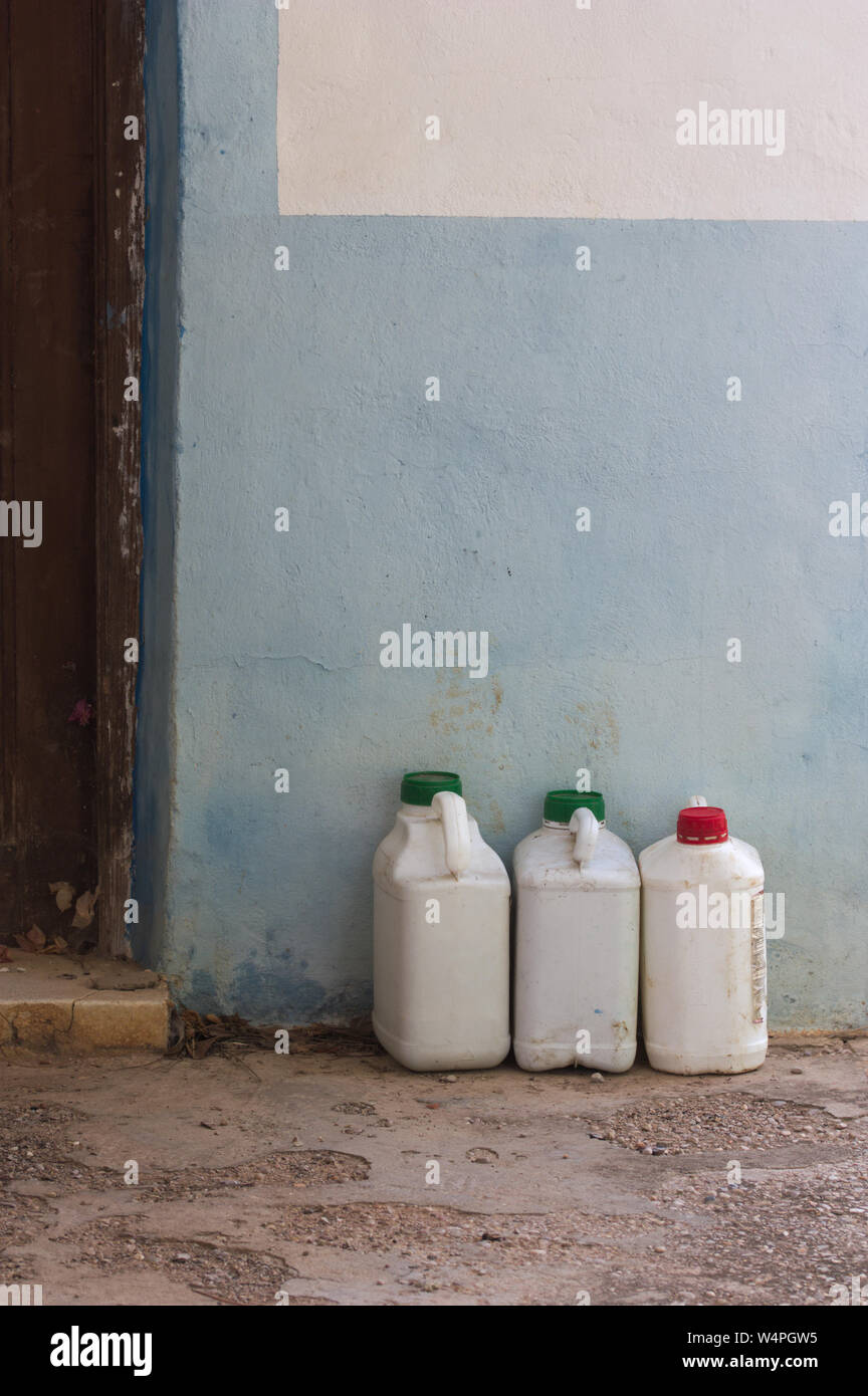 Three old insecticide containers forgotten next to a wall painted white ...