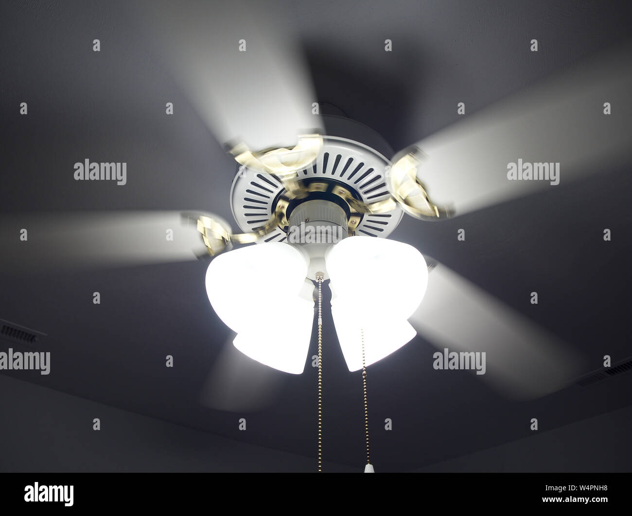 Ceiling fan with lights on and blades in motion Stock Photo - Alamy