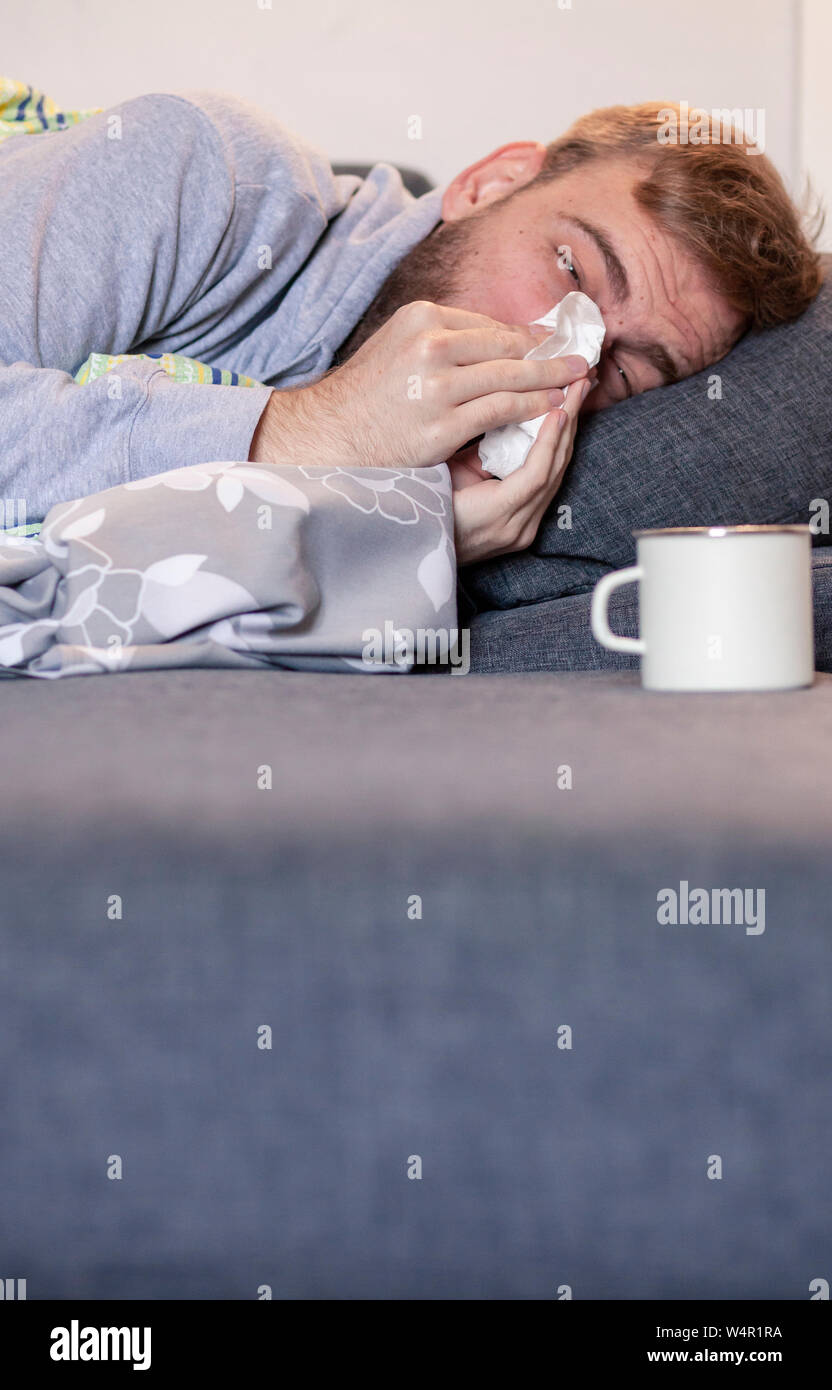 one young man, feeling sick, wiping his nose while laying in bed Stock ...