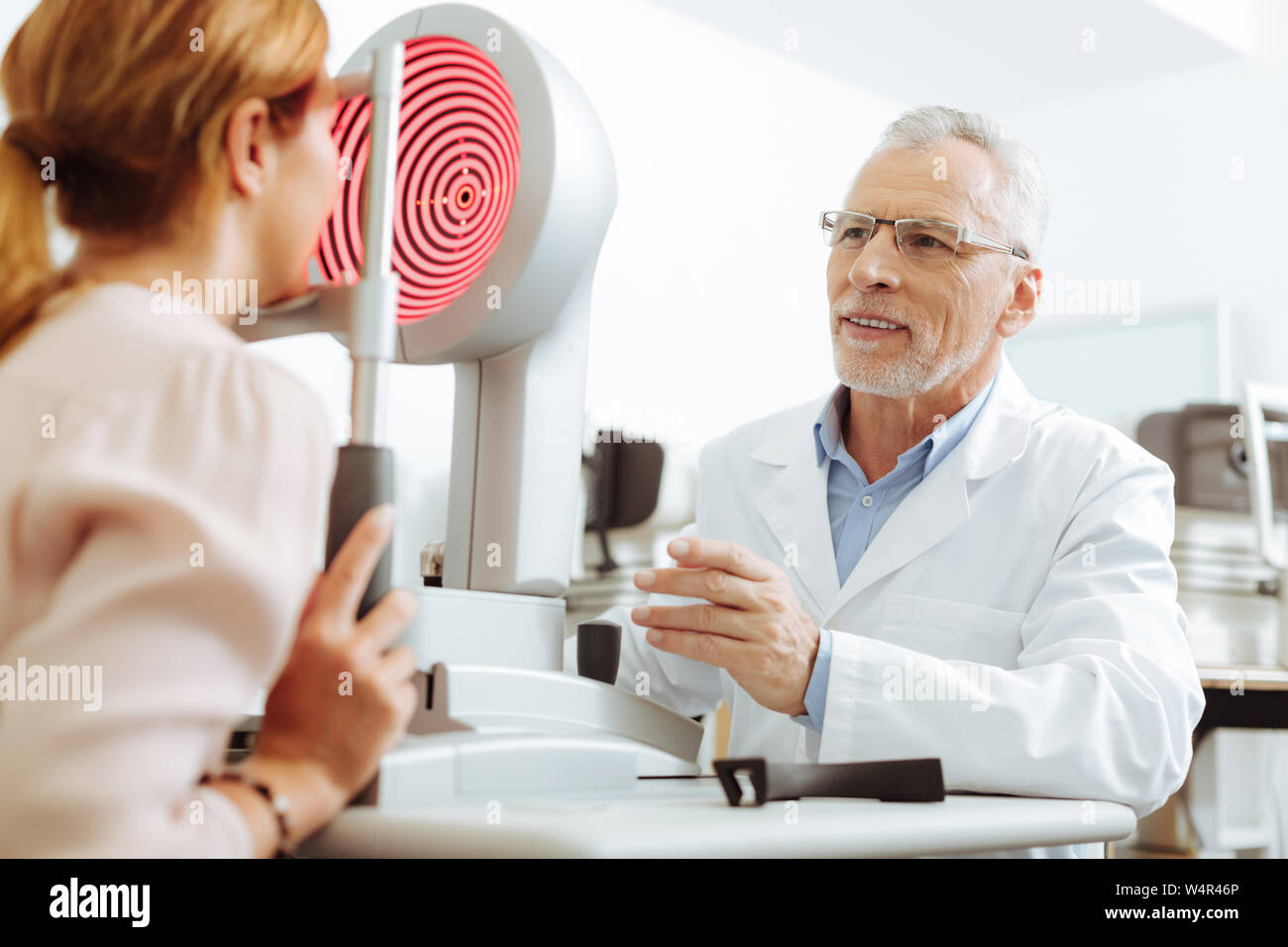 Eye therapist smiling. Grey-haired eye therapist in glasses smiling ...
