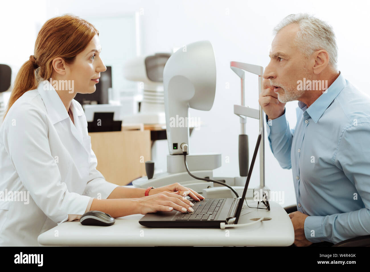 Eye specialist smiling. Pleasant eye specialist smiling while examining ...