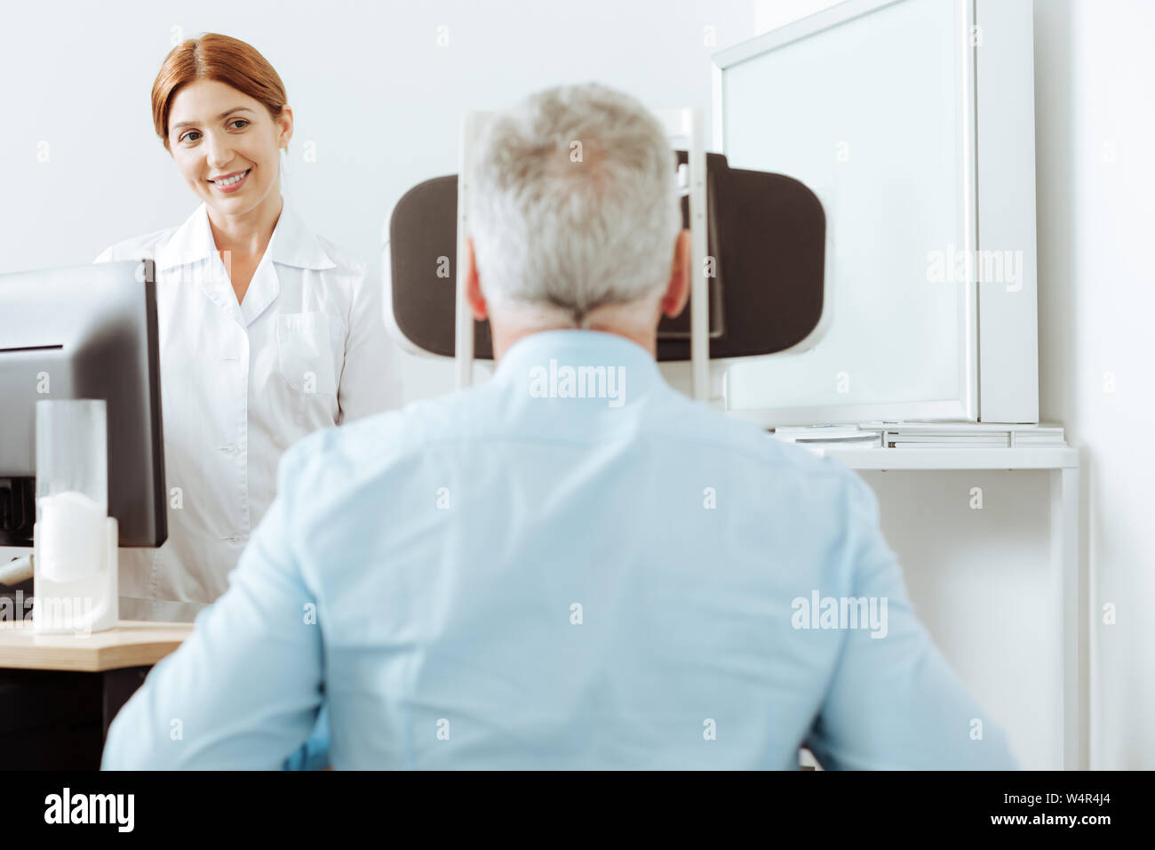 Ophthalmologist smiling. Red-haired professional ophthalmologist ...