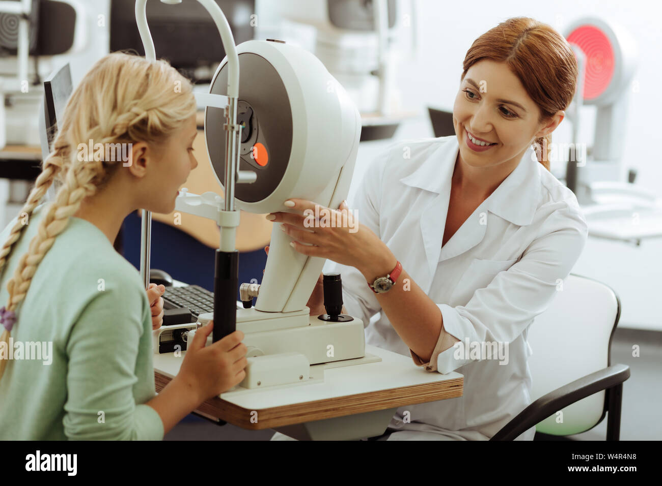 Visiting eye doctor. Cute blonde-haired girl feeling excited while ...