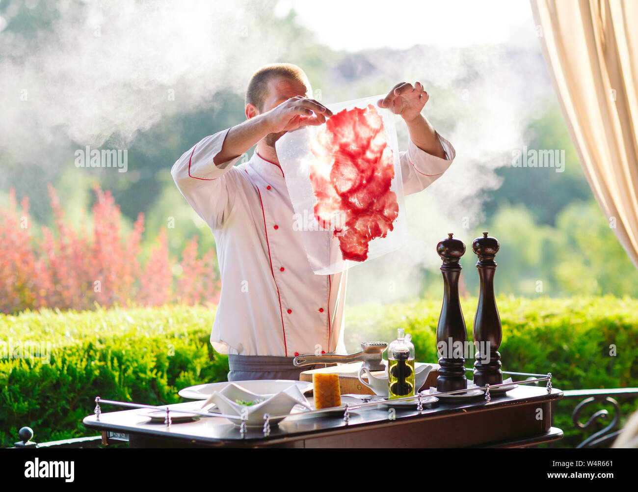A man cook cuts meat with a knife in a restaurant Stock Photo - Alamy